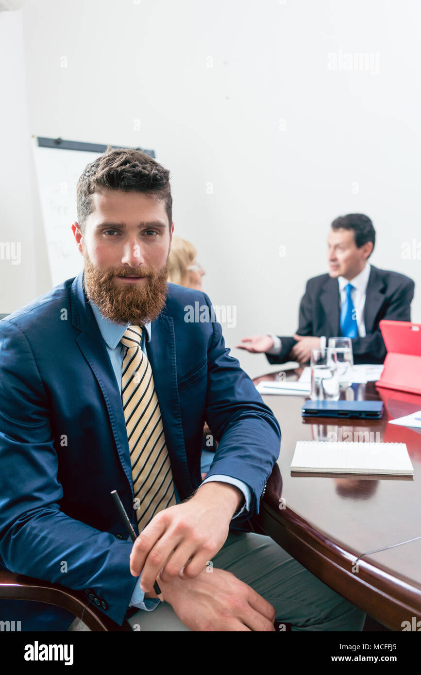 Portrait of a handsome young businessman looking at camera with ...