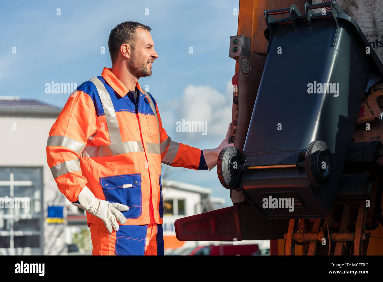 Garbage collection worker putting bin into waste truck Stock Photo - Alamy