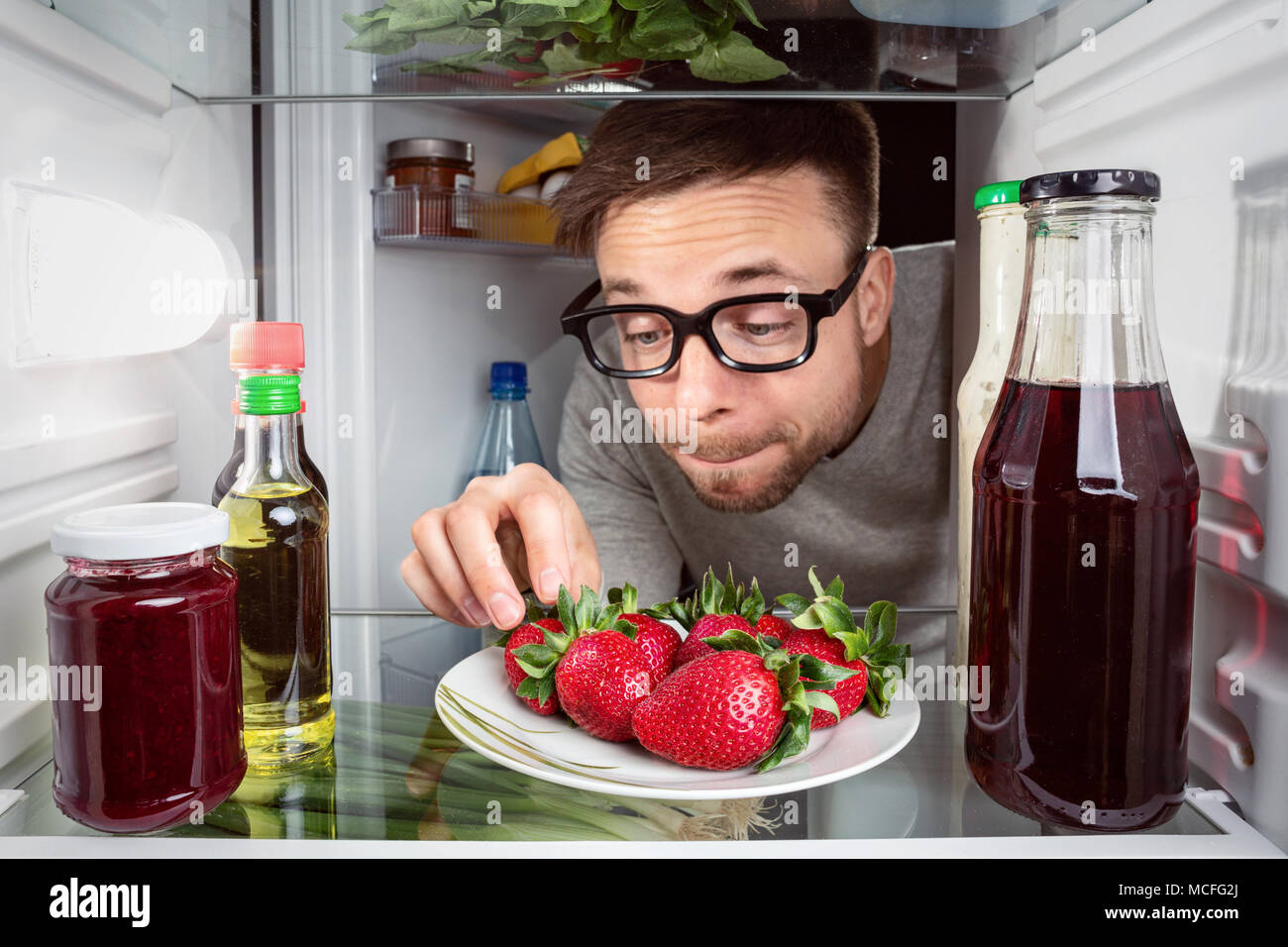 Man reaching for fresh strawberries in a fridge Stock Photo - Alamy