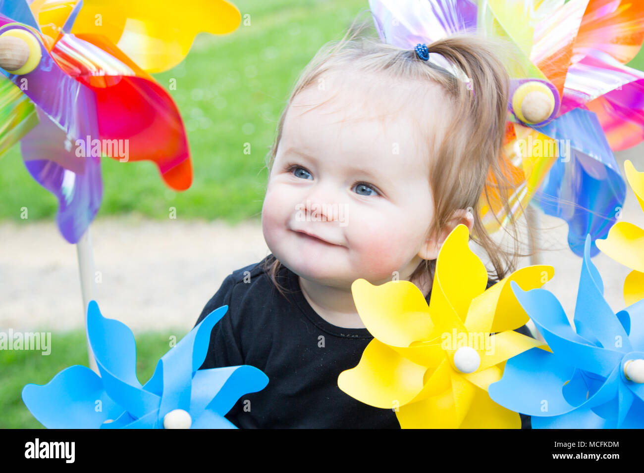 11 month old baby girl surrounded with colourful plastic windmills, UK ...