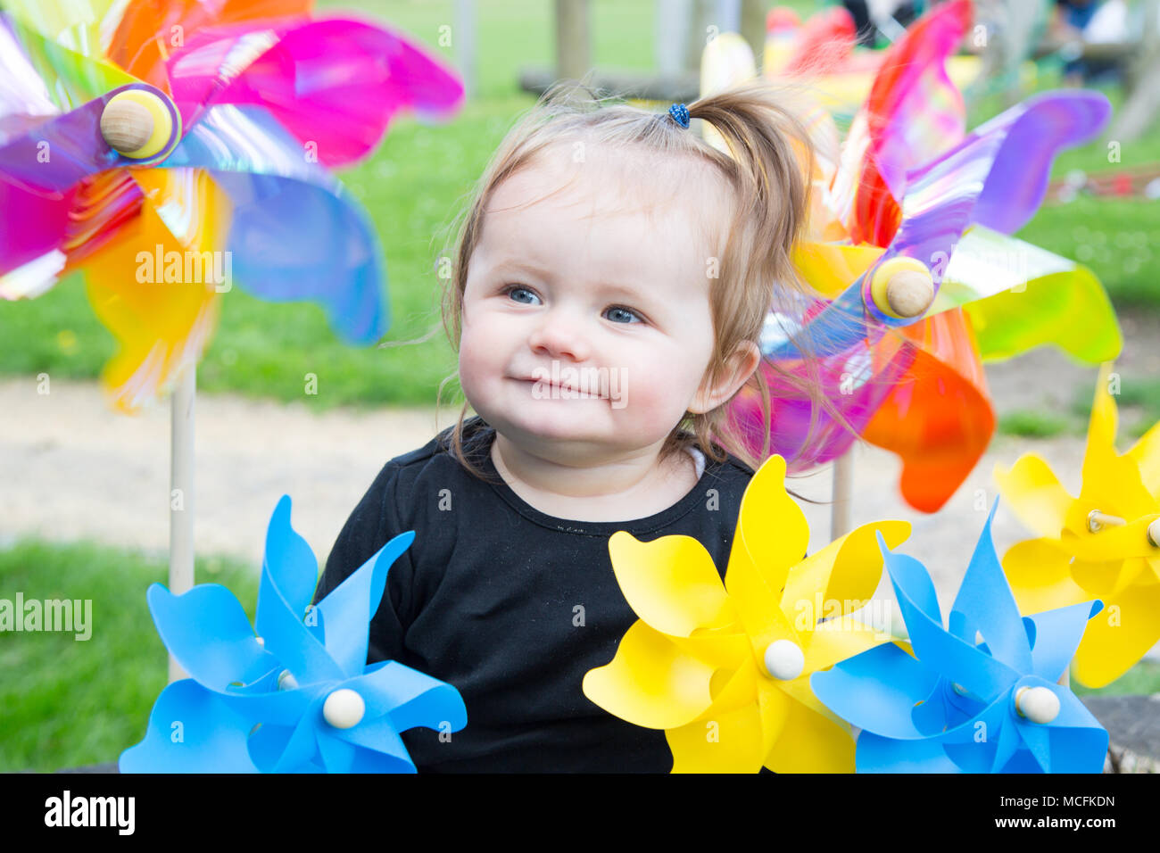 11 month old baby girl surrounded with colourful plastic windmills, UK ...