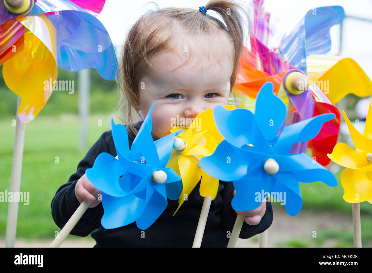 11 month old baby girl surrounded with colourful plastic windmills, UK ...