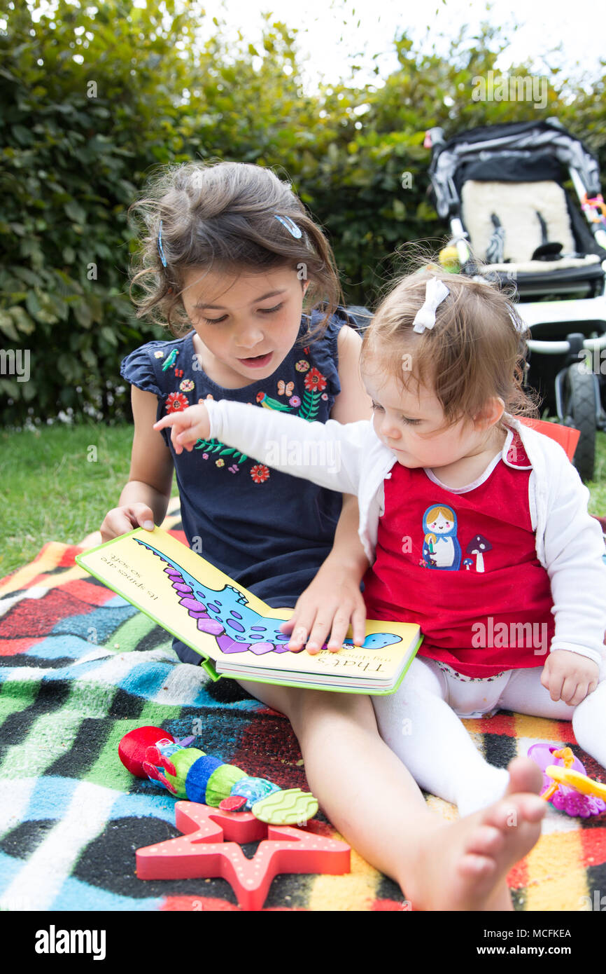 Big sister reading to her toddler sister Stock Photo - Alamy