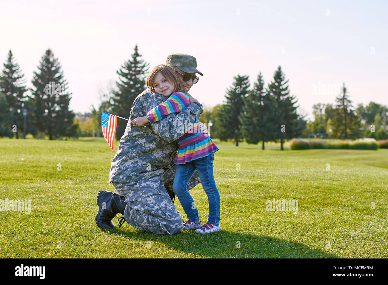 Soldier reunited with his daughter. Child with usa flag is hugging her ...