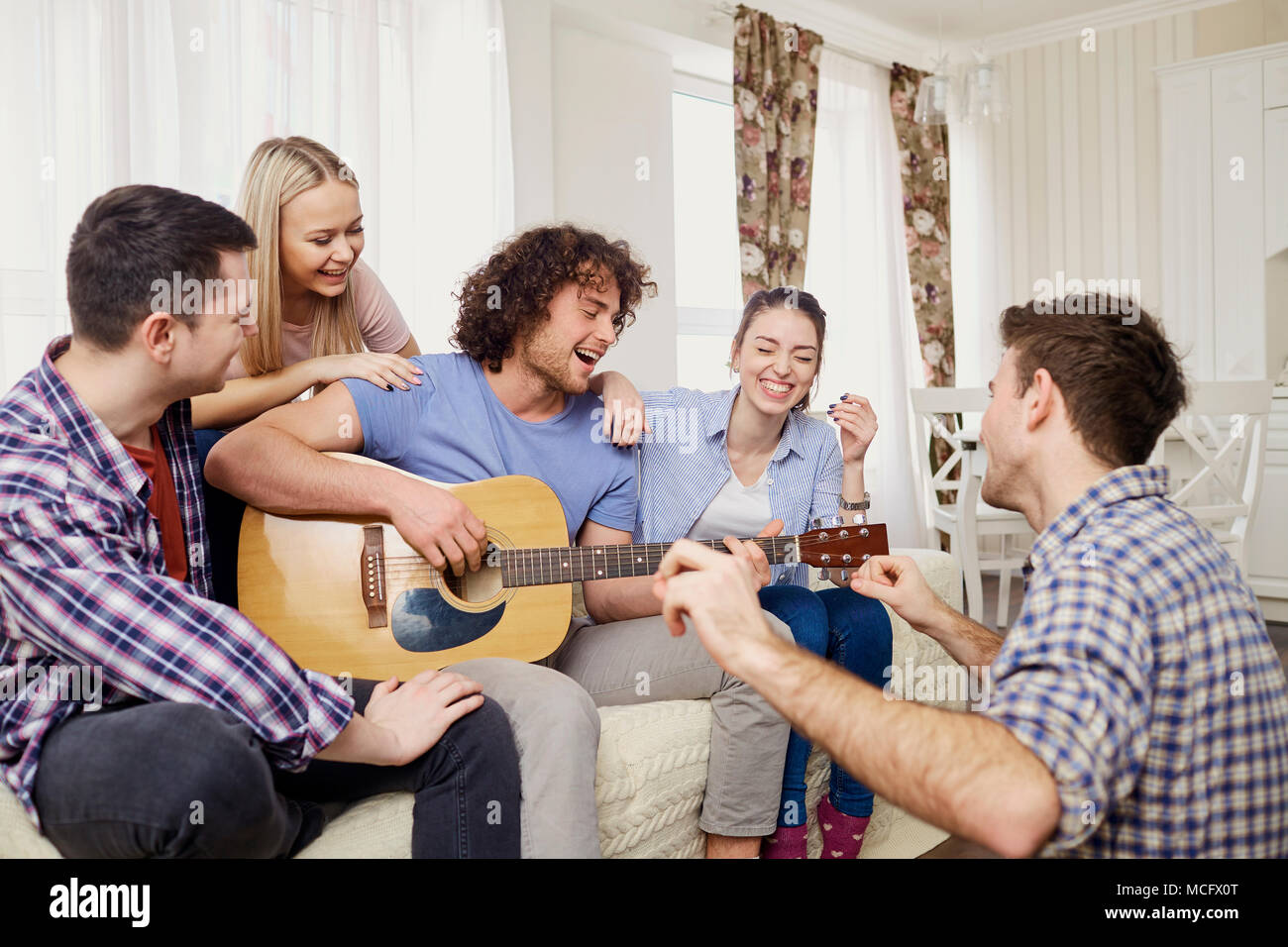 A group of friends with a guitar sing fun songs at a party indoor Stock ...
