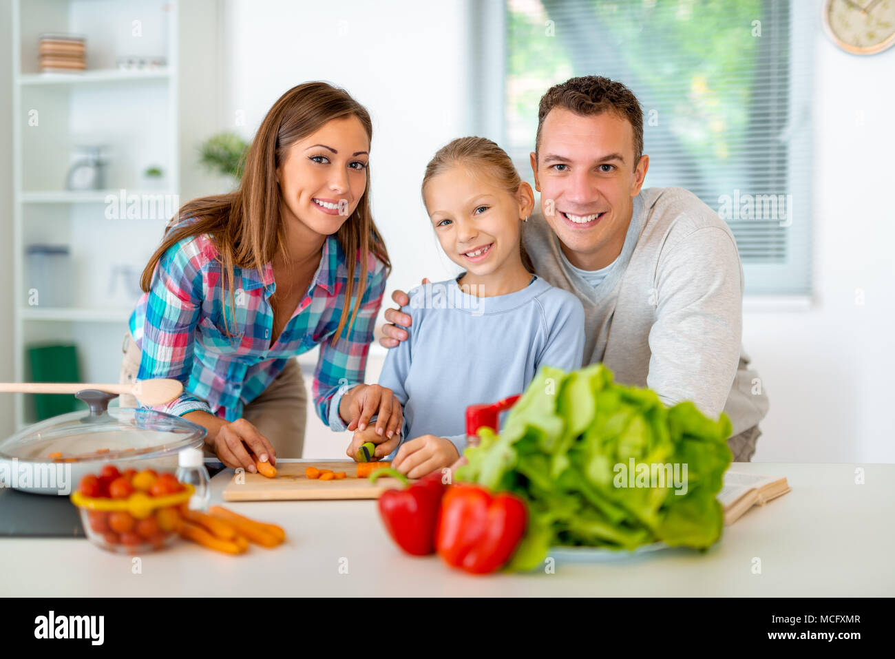 Beautiful young family cooking healthy meal in the domestic kitchen ...