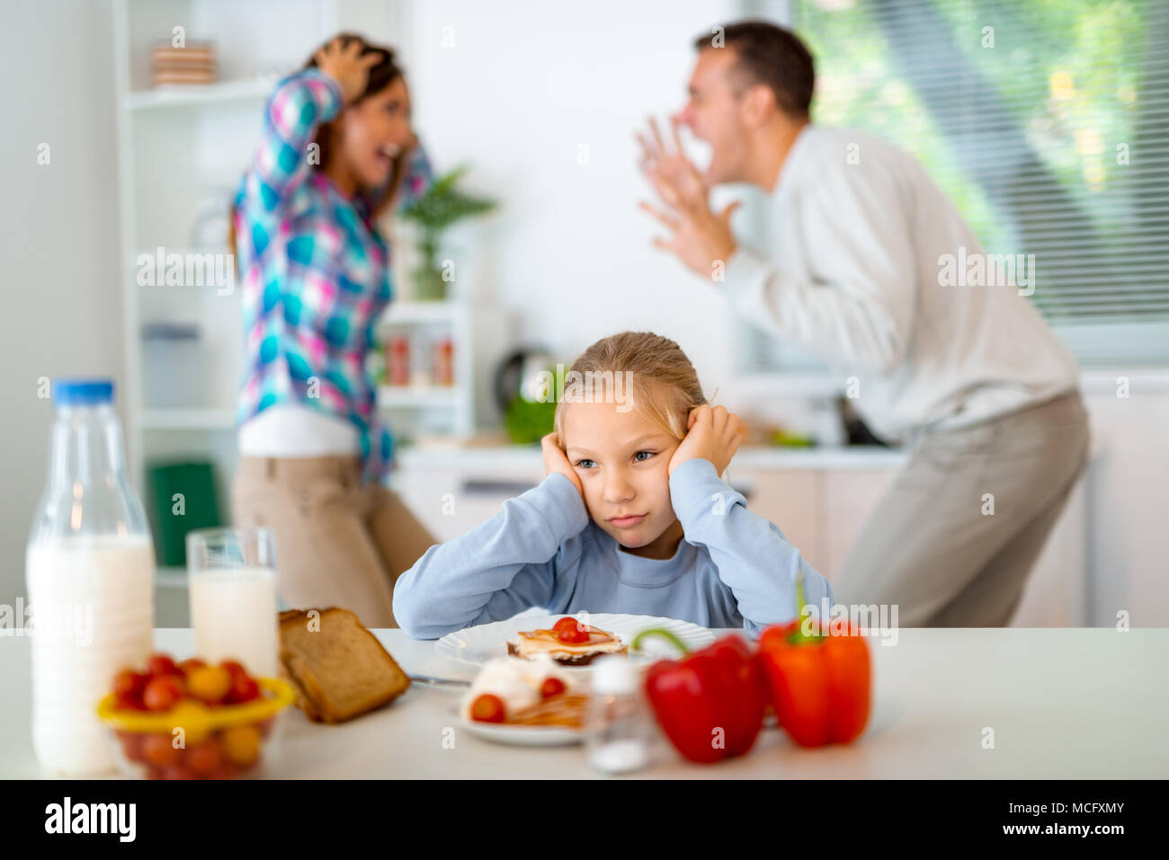 Sad little girl having breakfast while parents quarreling in the ...