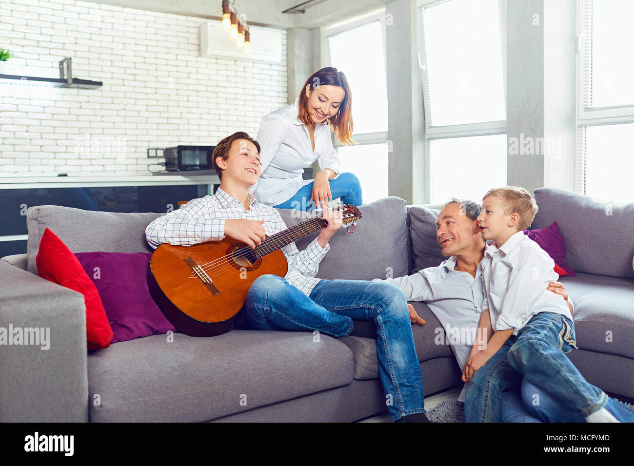 Happy family with guitar singing songs sitting in the room Stock Photo ...
