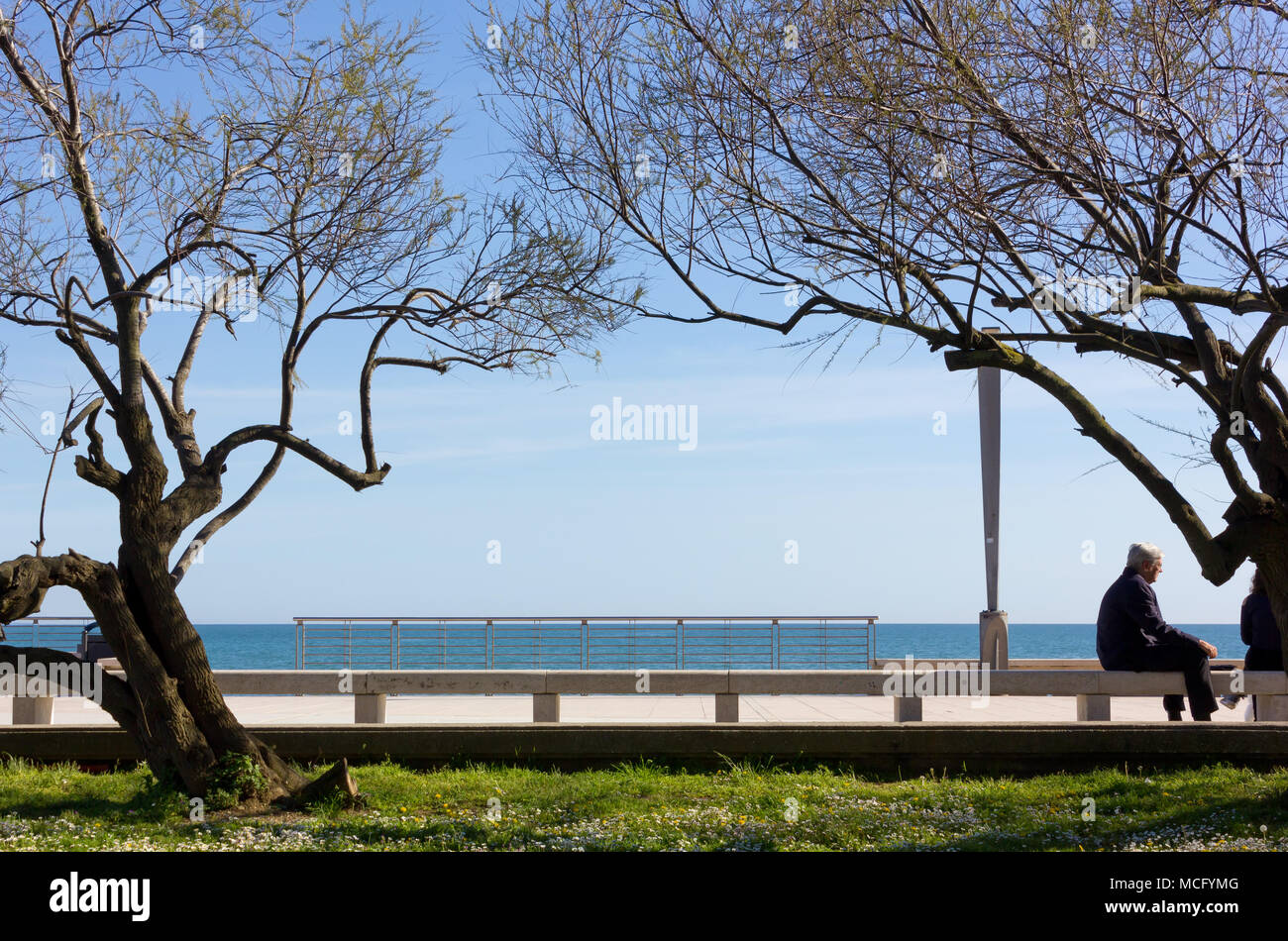 GRADO, Italy - April 13, 2018: Seafront promenade with a man seated on ...