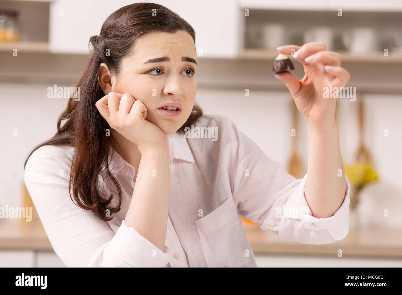 Sad unsatisfied woman examining candy Stock Photo - Alamy