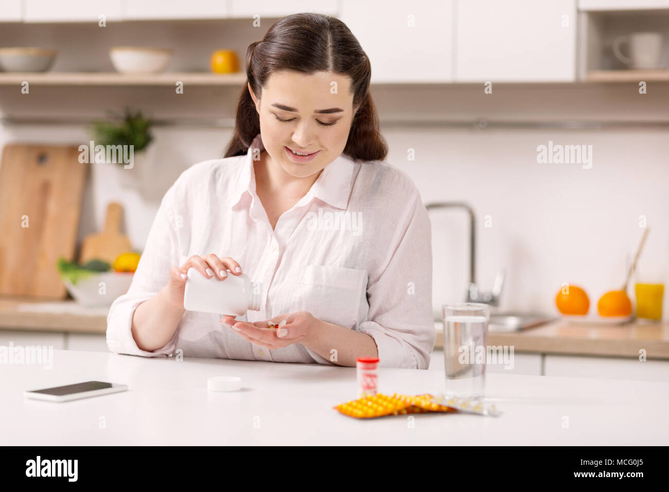 Charming glad woman taking pills Stock Photo - Alamy