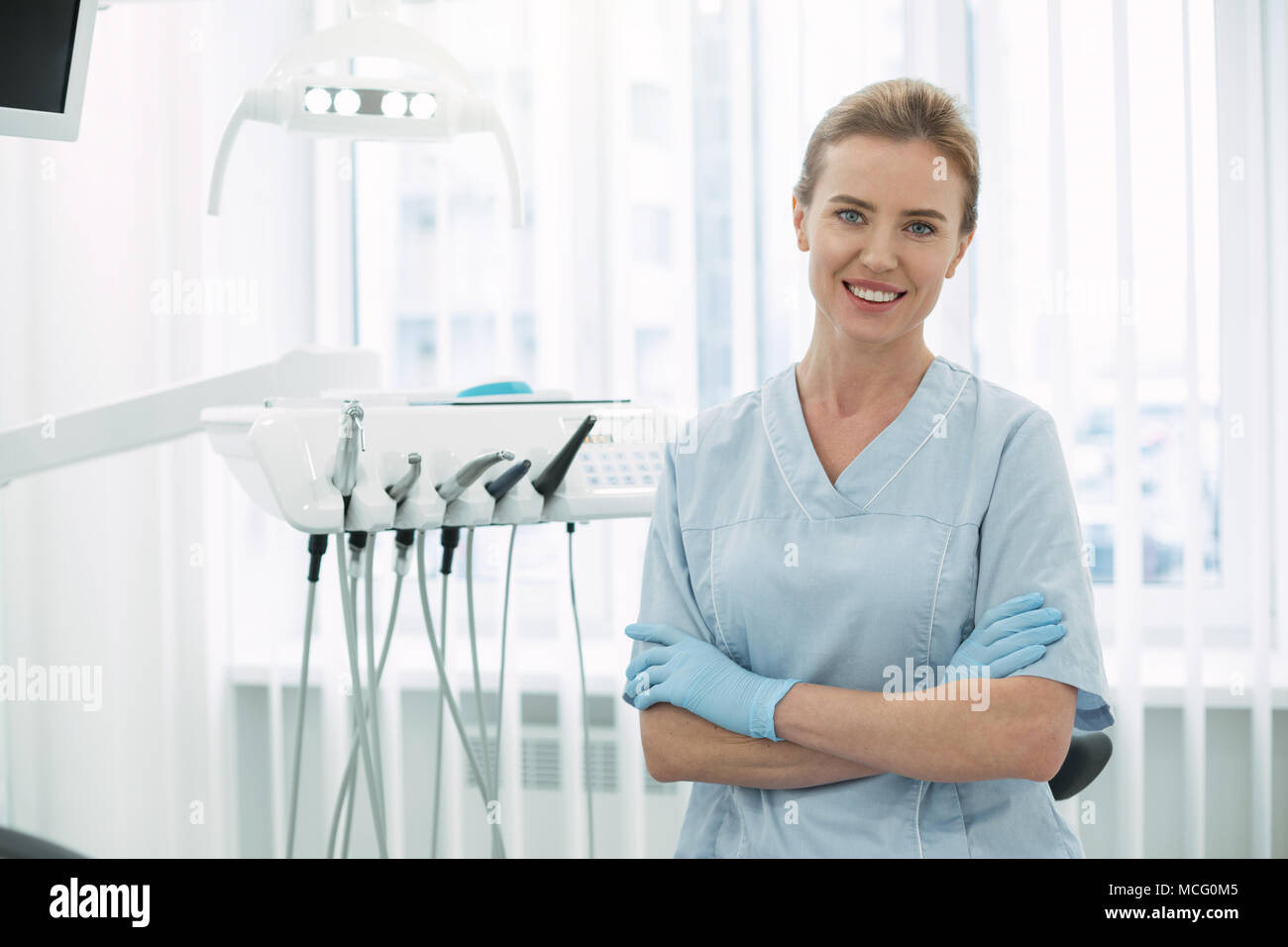 Inspired dentist standing with her arms crossed Stock Photo - Alamy