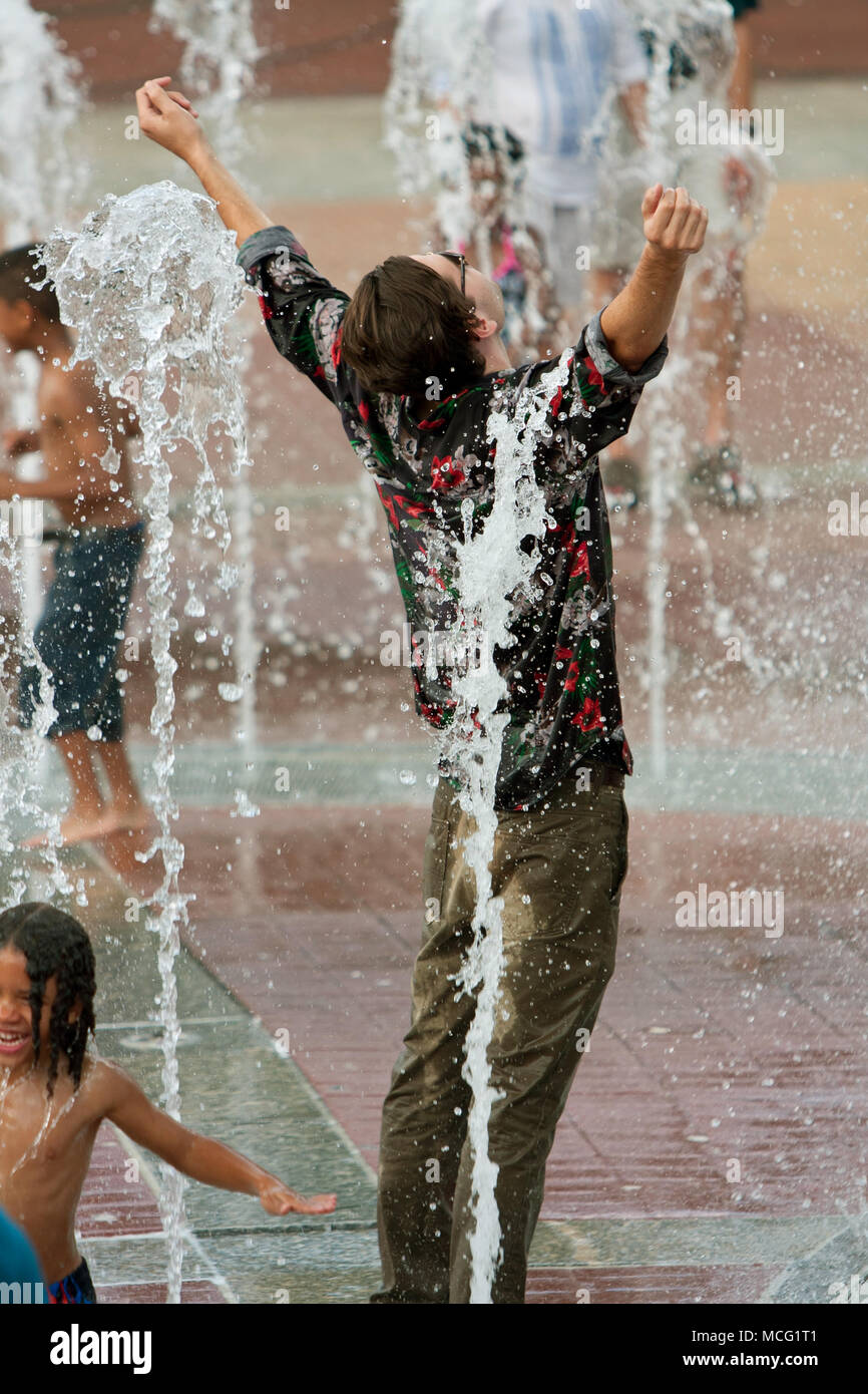 A young man poses triumphantly while getting soaked wearing street ...