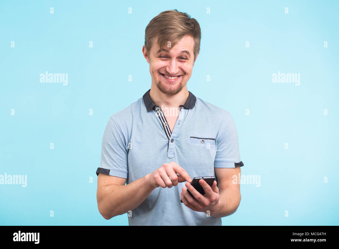 Funny man texting message on smart phone isolated on blue background ...