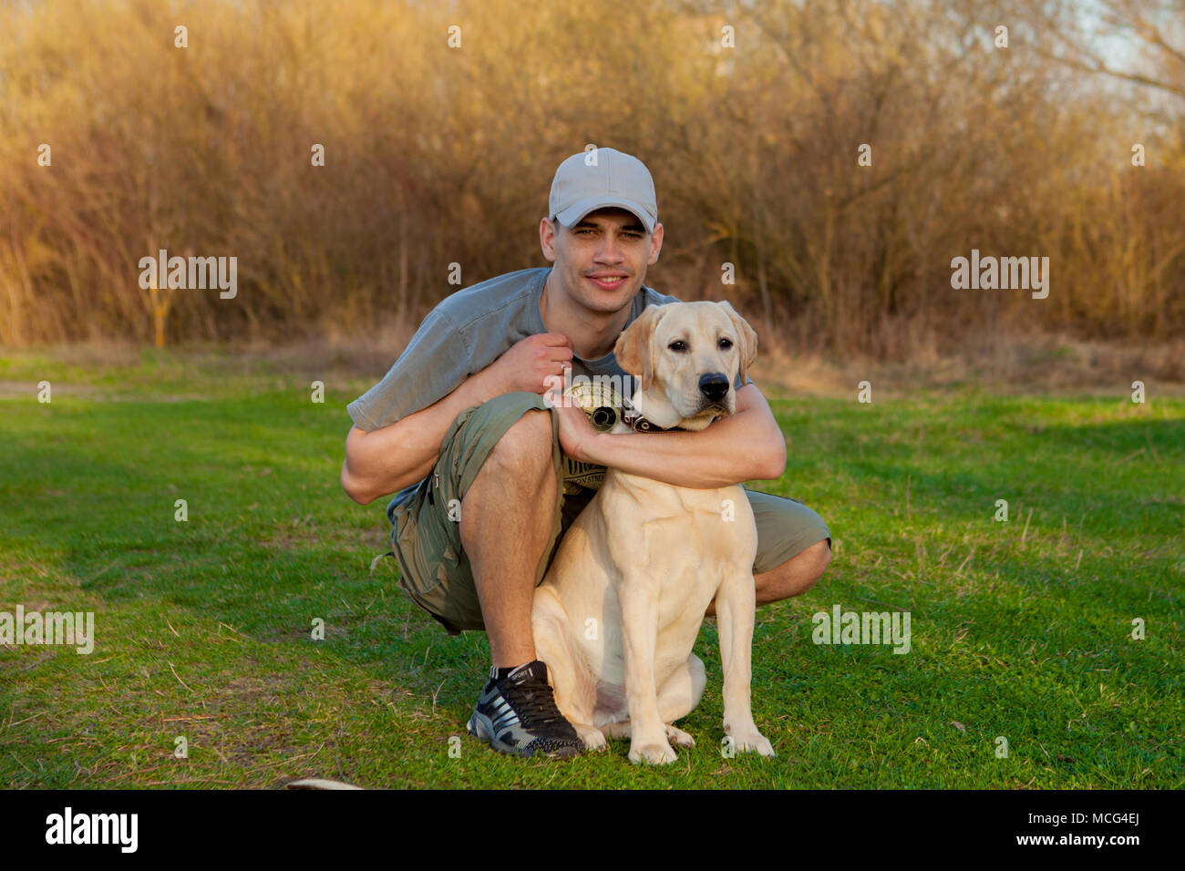 Young guy with labrador on walk in summer park. Educating dog. Play ...