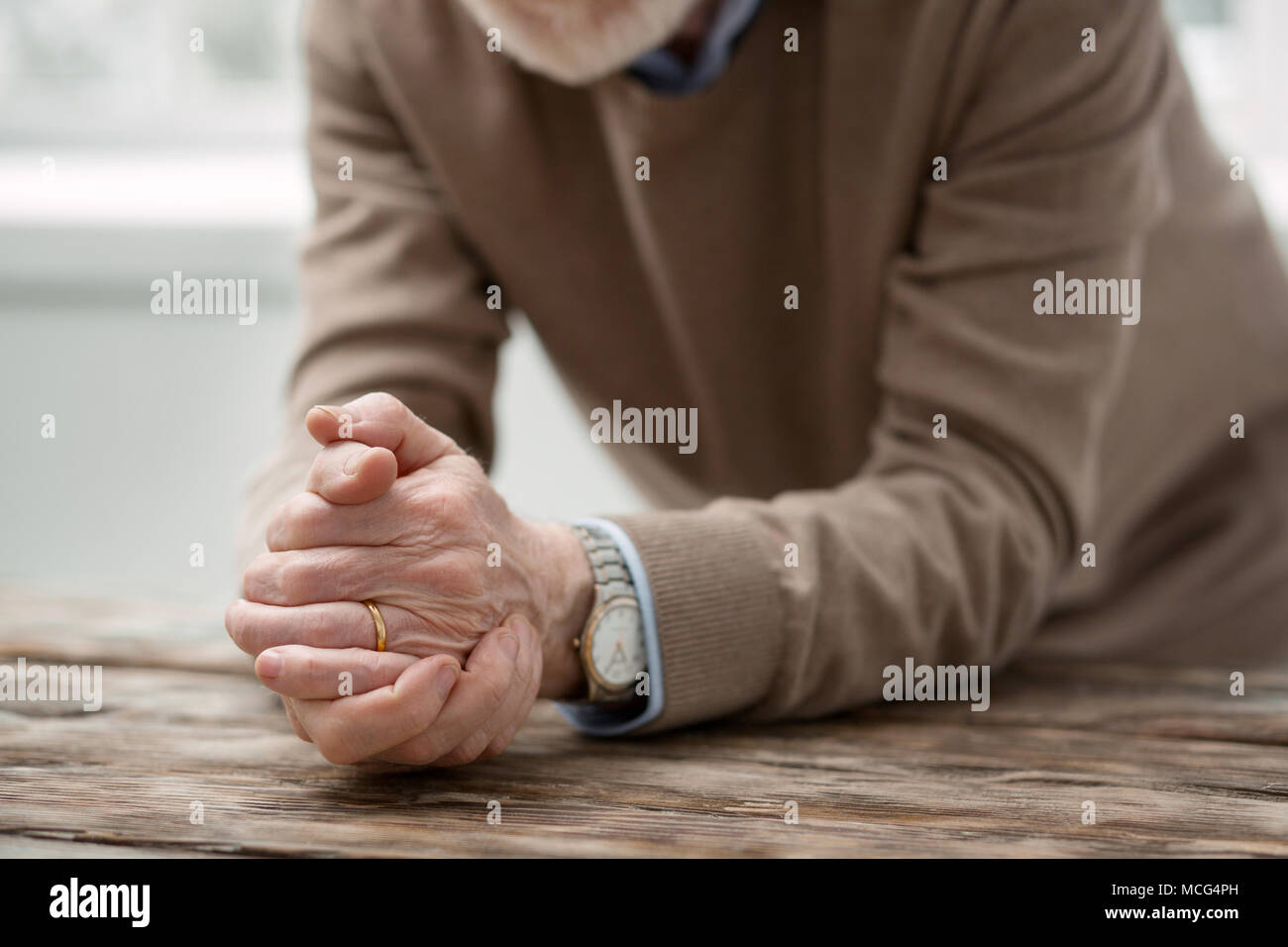Nice aged man putting hands on the table Stock Photo - Alamy