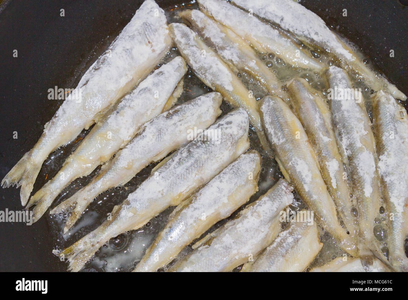 Cooking fried fish smelt rolled in flour Stock Photo - Alamy