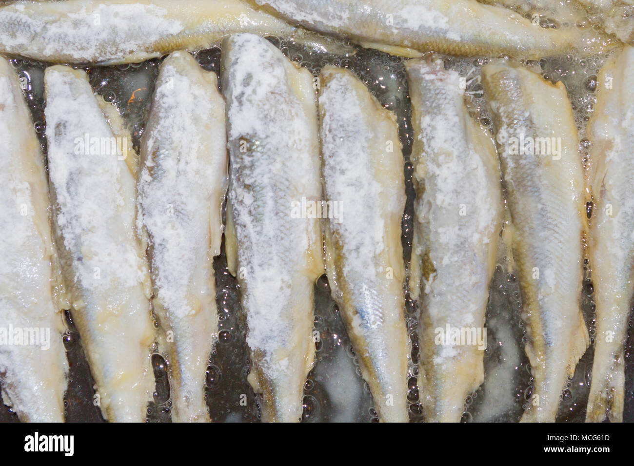 Cooking fried fish smelt rolled in flour Stock Photo - Alamy