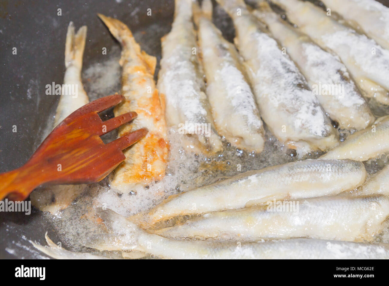 Cooking fried fish smelt rolled in flour Stock Photo - Alamy