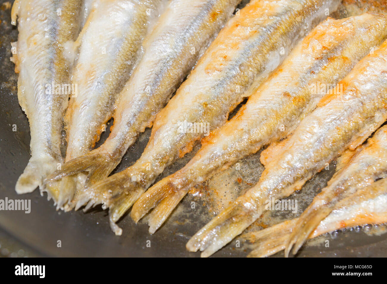 Cooking fried fish smelt rolled in flour Stock Photo - Alamy