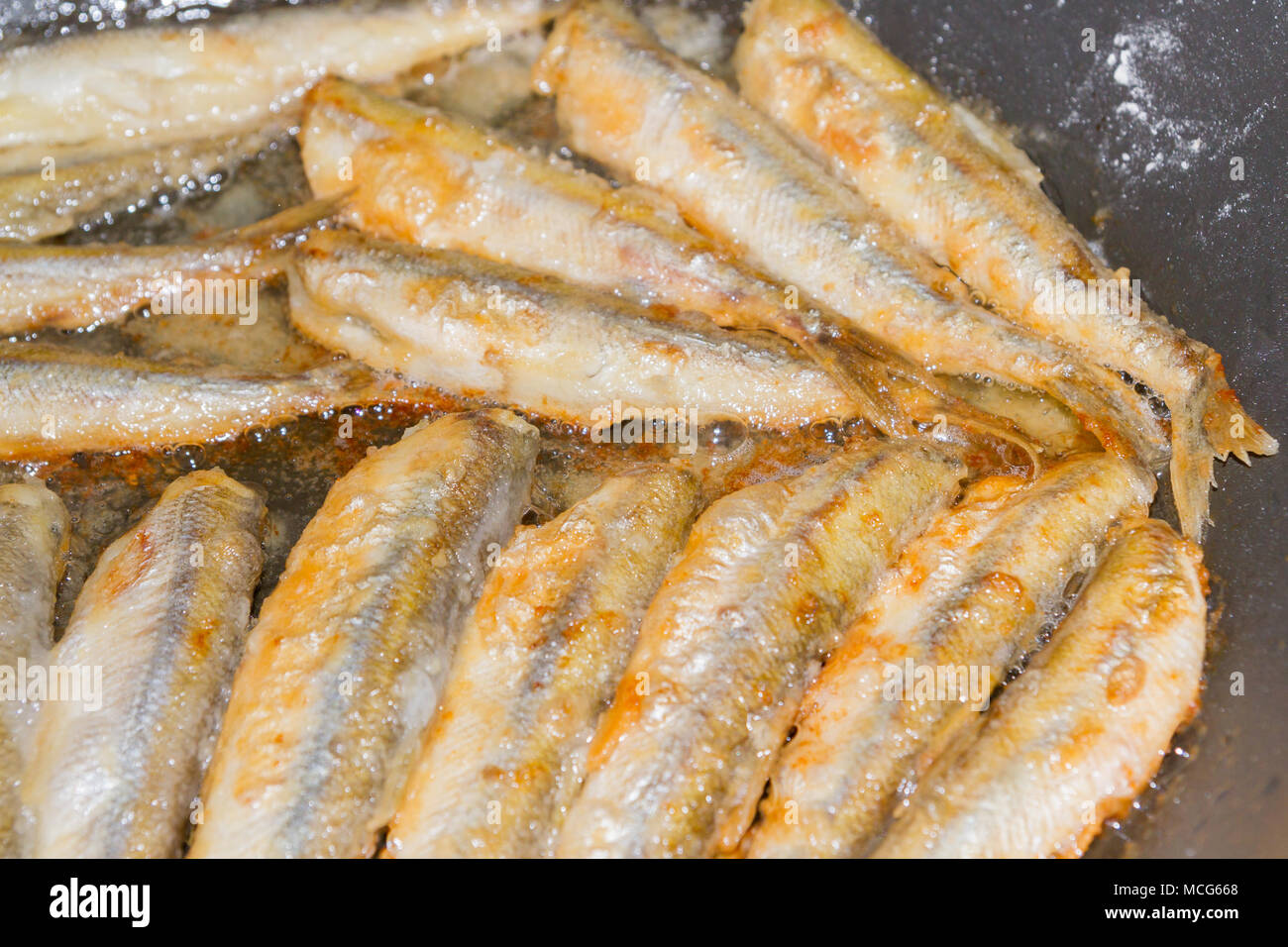 Cooking fried fish smelt rolled in flour Stock Photo - Alamy