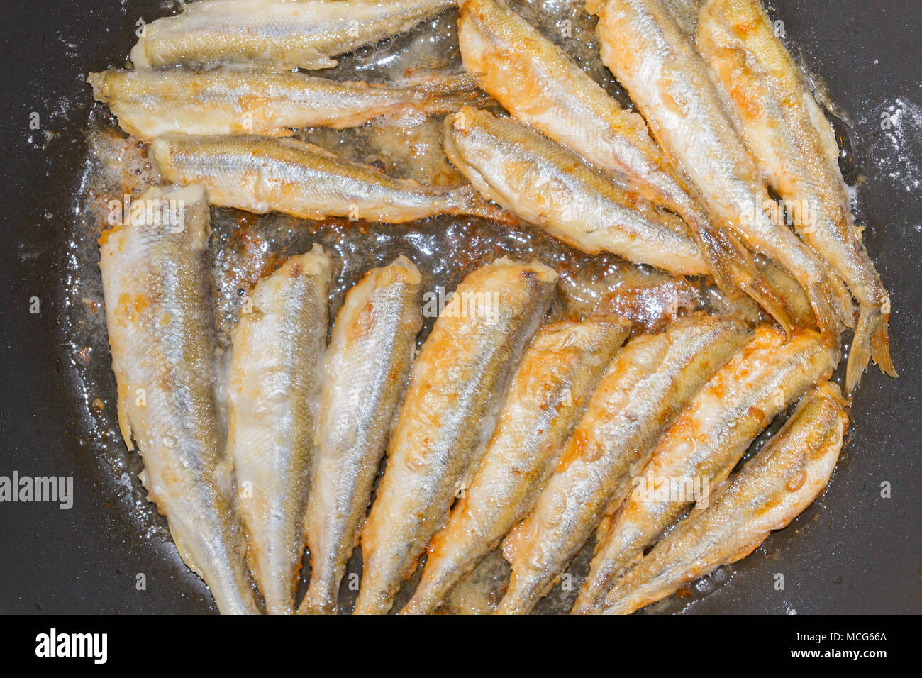 Cooking fried fish smelt rolled in flour Stock Photo - Alamy