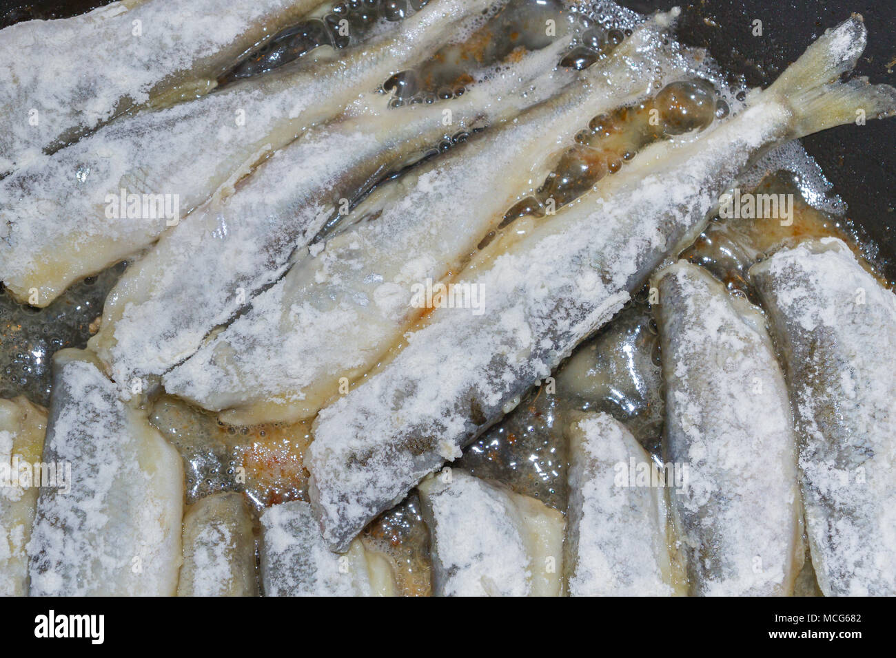 Cooking fried fish smelt rolled in flour Stock Photo - Alamy