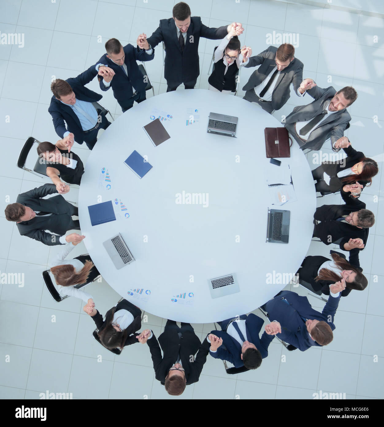 large business team sitting at the round table and raising his hands up ...