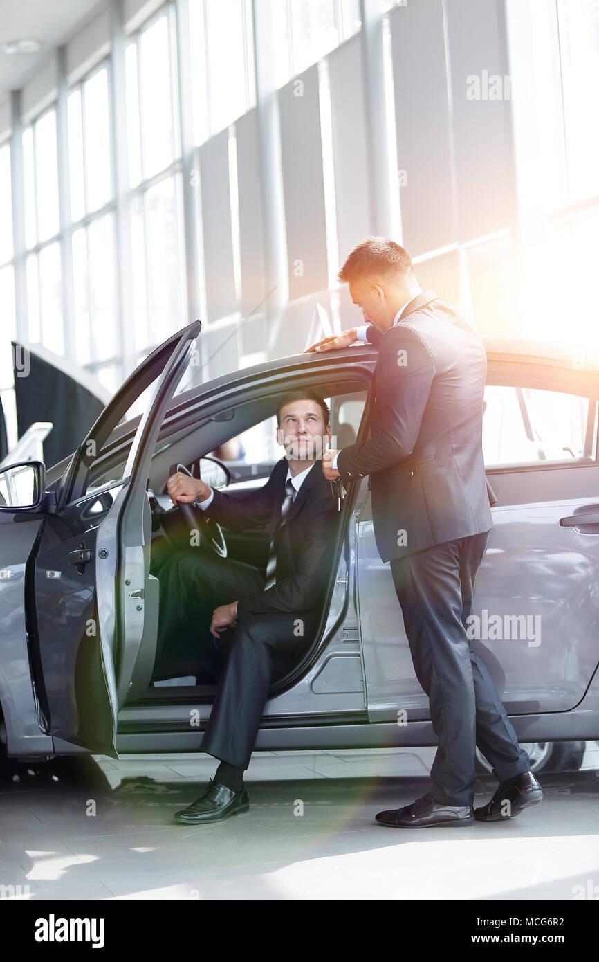 businessman receives from the Manager the keys,sitting behind the wheel ...