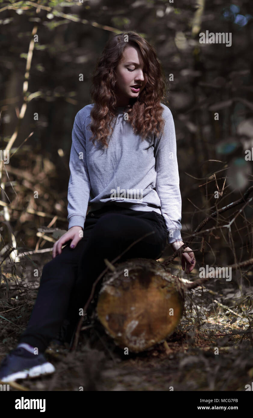 beautiful young woman sitting on a log Stock Photo - Alamy