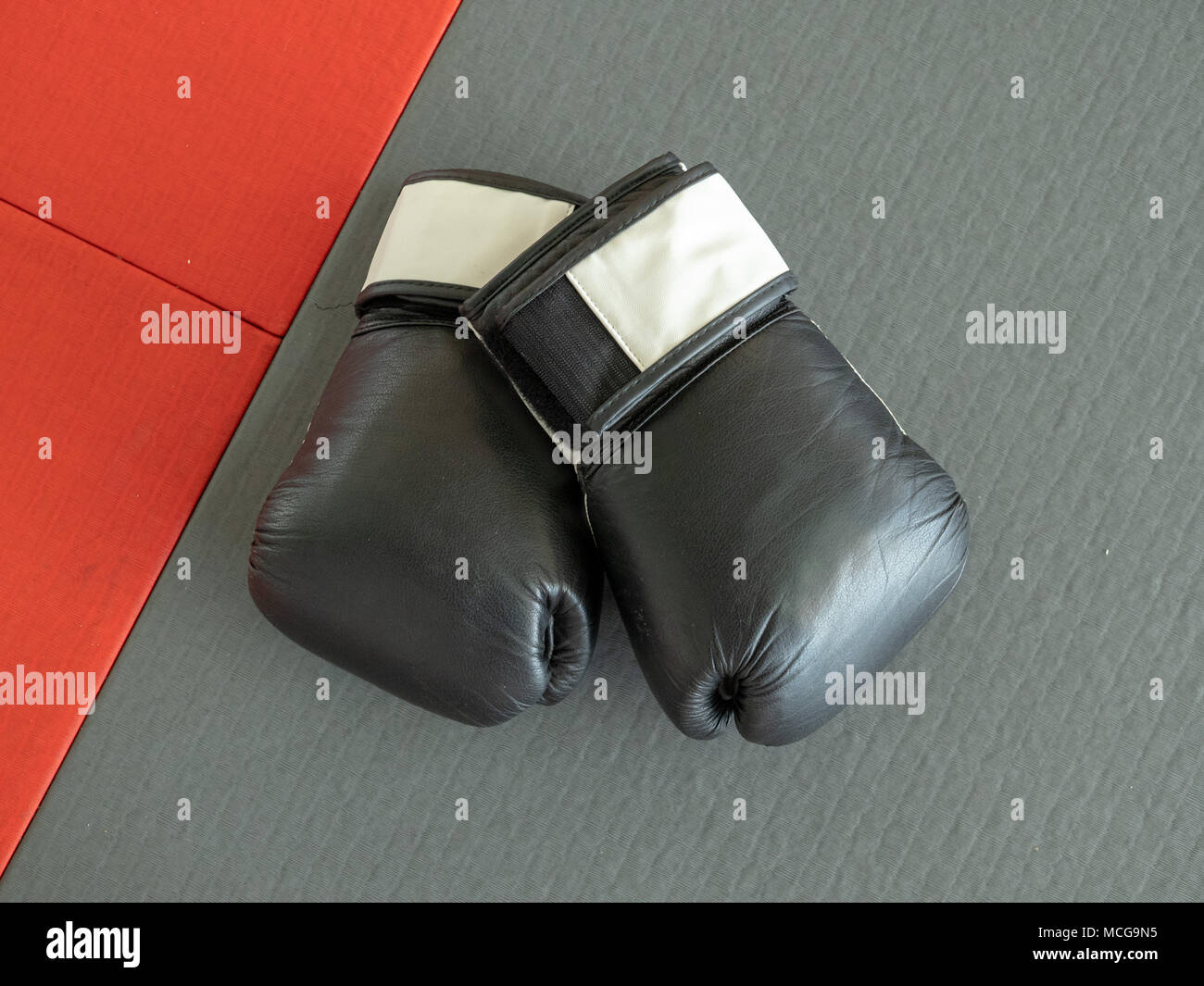 Black boxing gloves sitting on the mats of a boxing gym on black and ...
