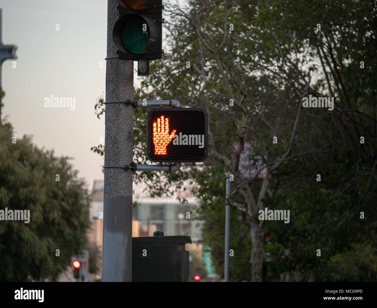 A pedestrian stop sign appears on a crosswalk on a busy urban street ...