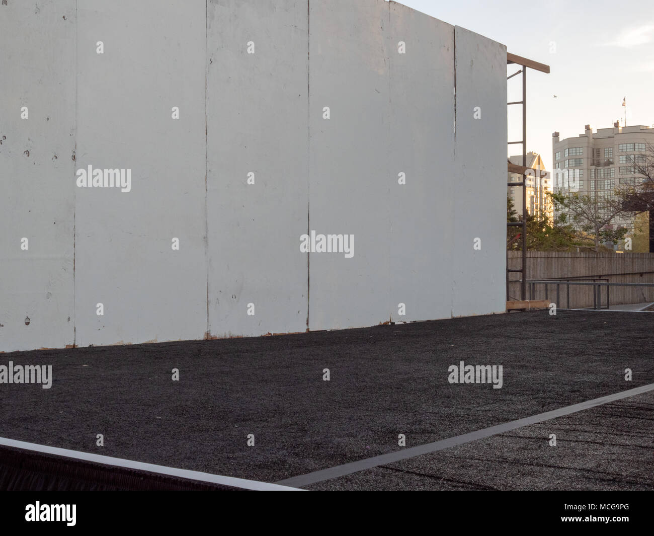 Angled view of a hastily built outdoor stage with a white wall ready to ...