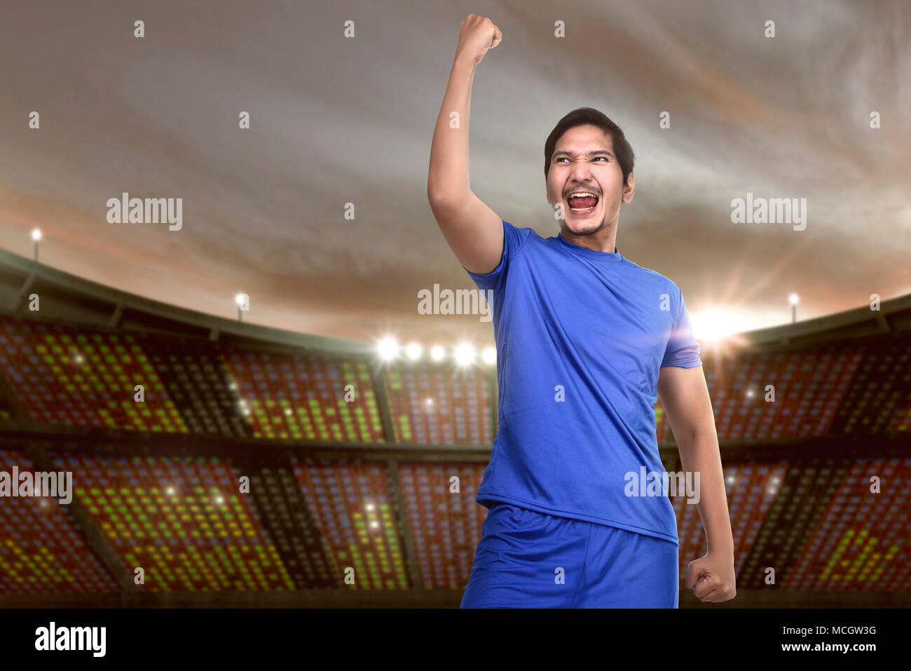 Excited asian footballer with blue jersey celebrating on stadium Stock ...
