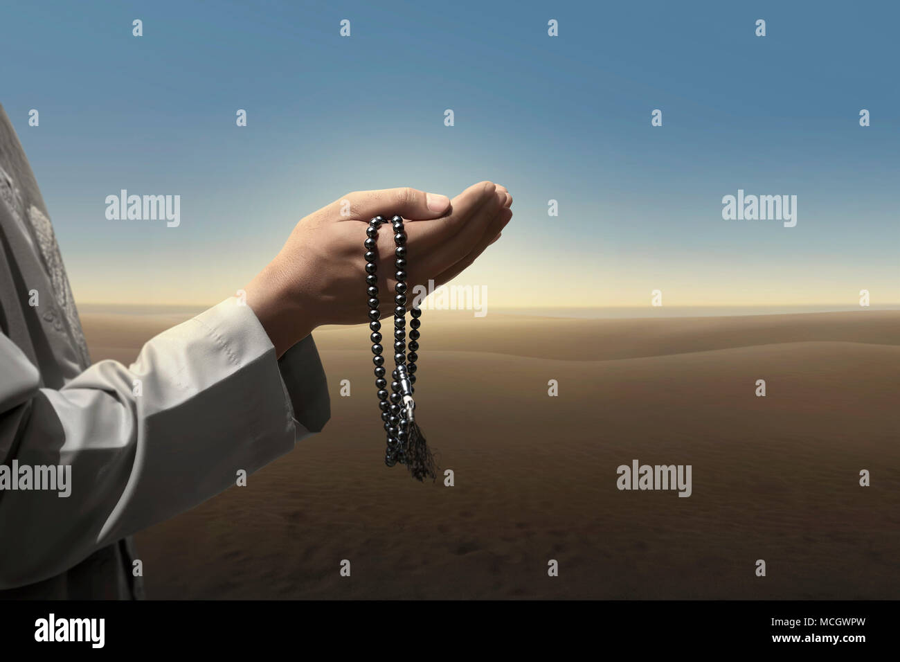 Muslim man pray with prayer beads over blue sky background Stock Photo ...