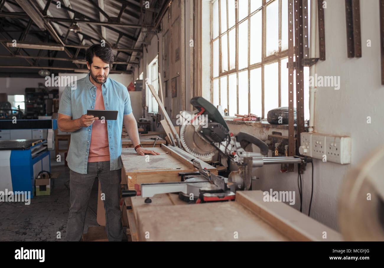Skilled young woodworker standing at mitre saw workbench in his ...