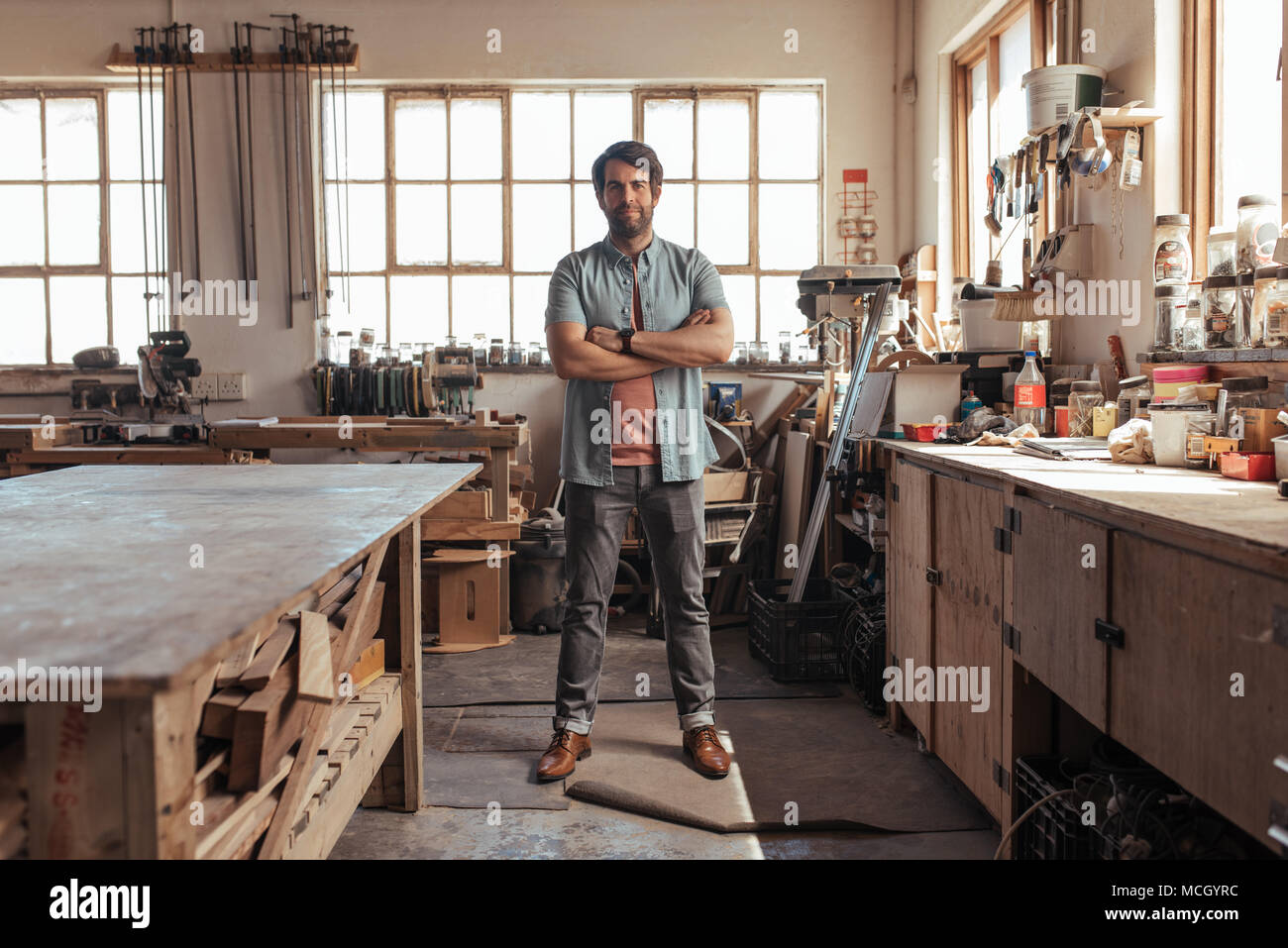 Portrait of a skilled young woodworker standing confidently with his ...