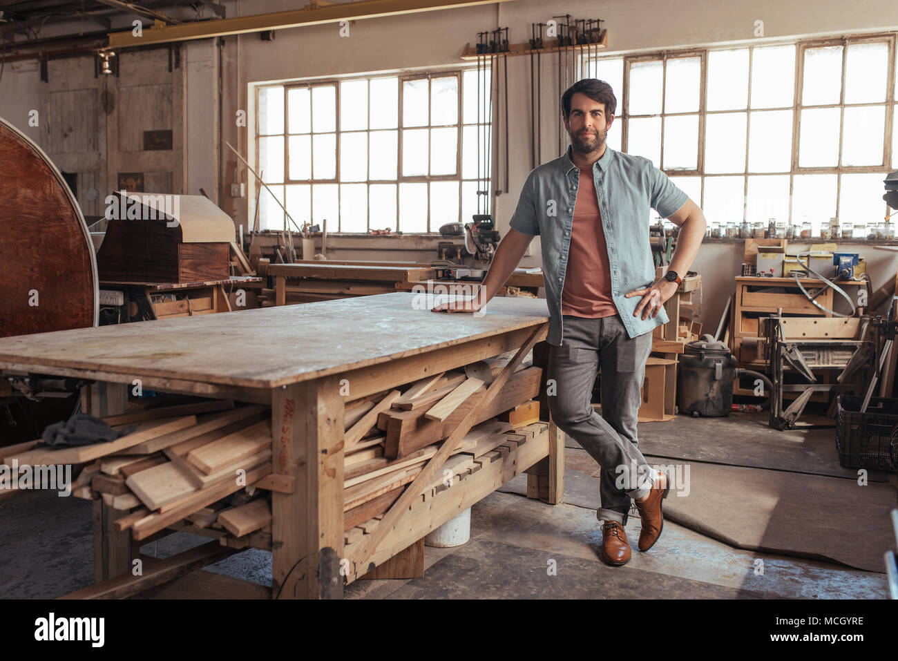 Portrait of a confident young woodworker standing next to a workbench ...