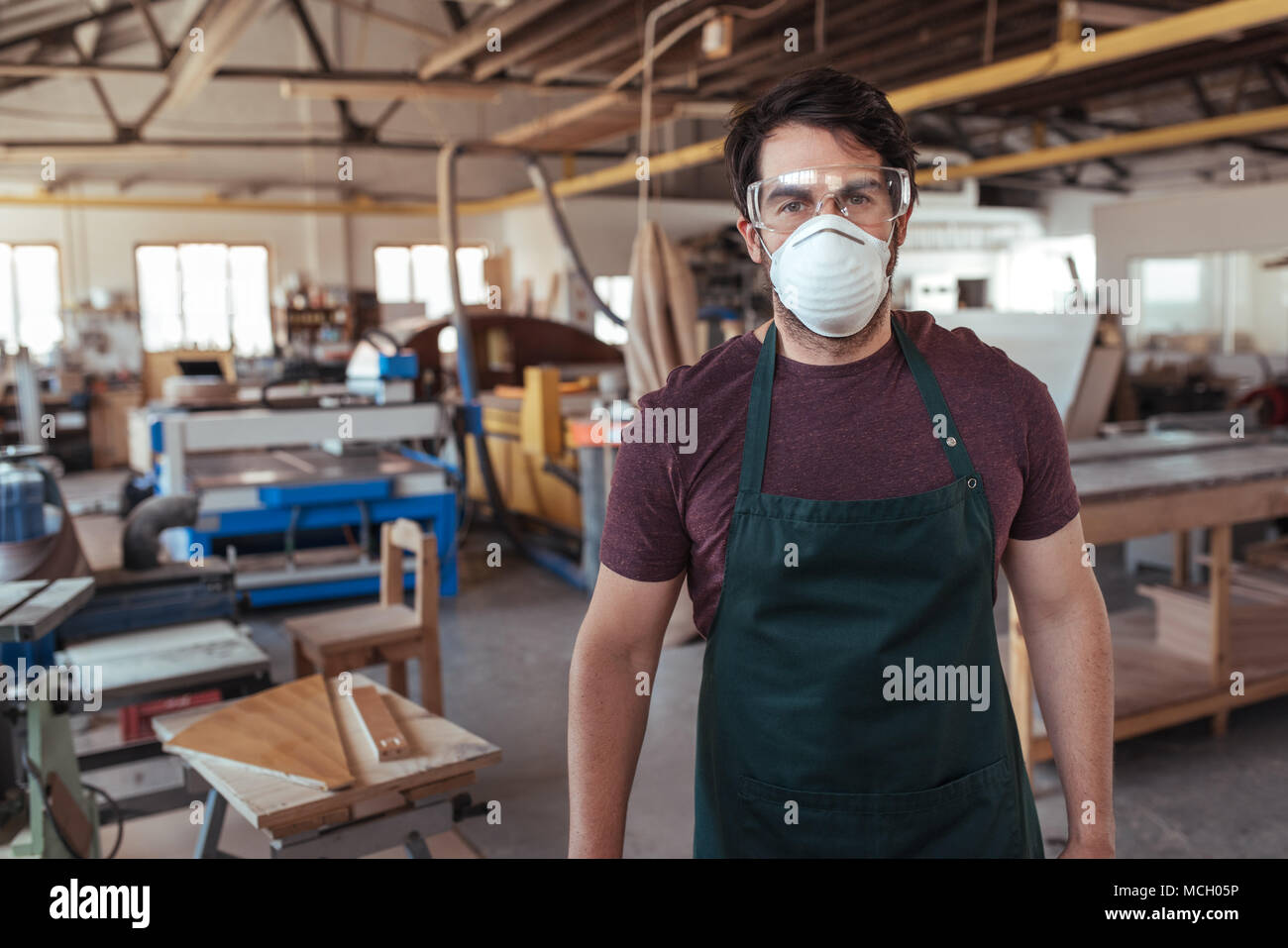 Portrait of a young craftsman wearing an apron and a protective mask ...