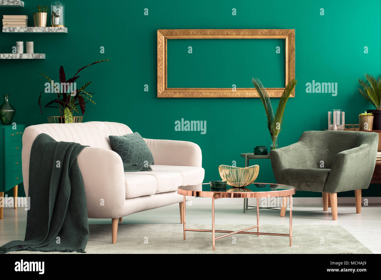 Copper table between beige settee and armchair in green living room ...