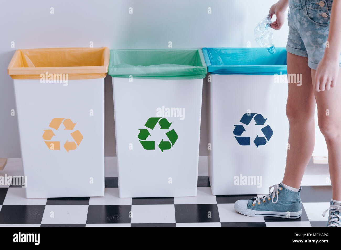 Kid throwing out a plastic bottle into a blue bin. Child recycling ...