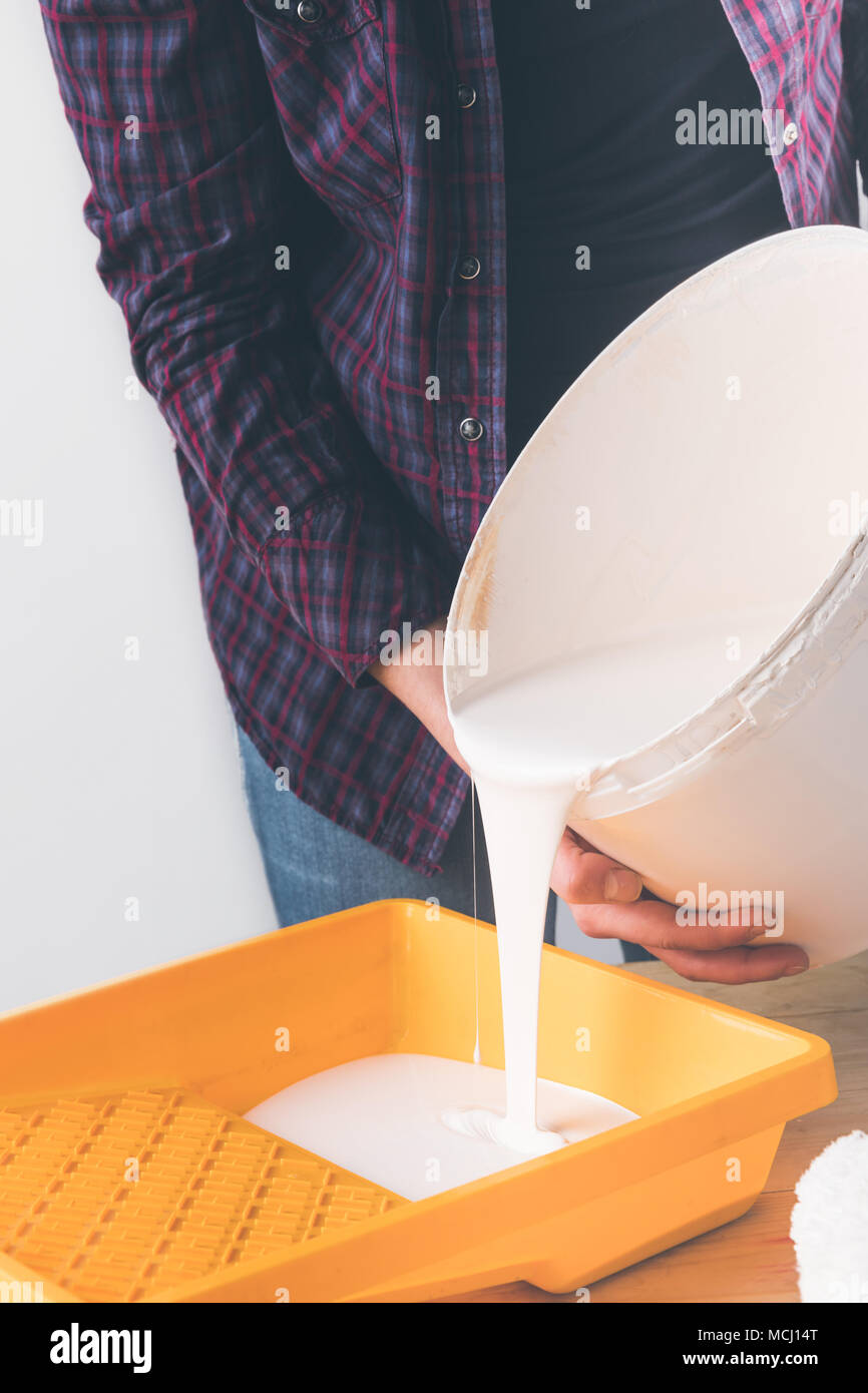 cropped image of girl pouring white paint into plastic tray Stock Photo ...