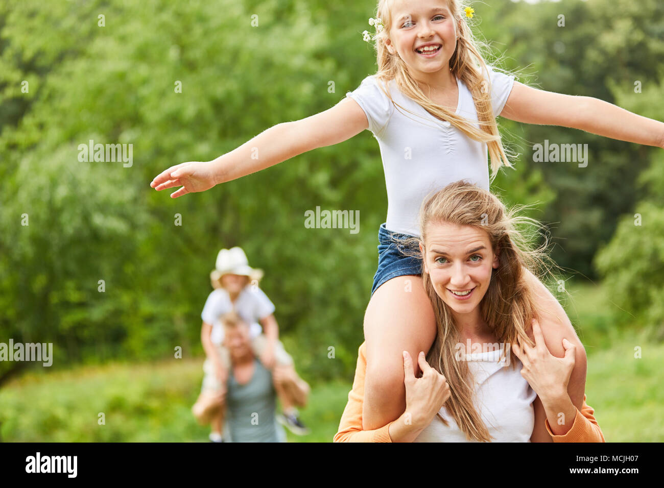 Girl is having fun on a hike in mother's piggyback Stock Photo - Alamy