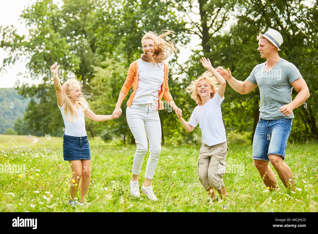 Happy family and children are happily dancing together in the garden ...
