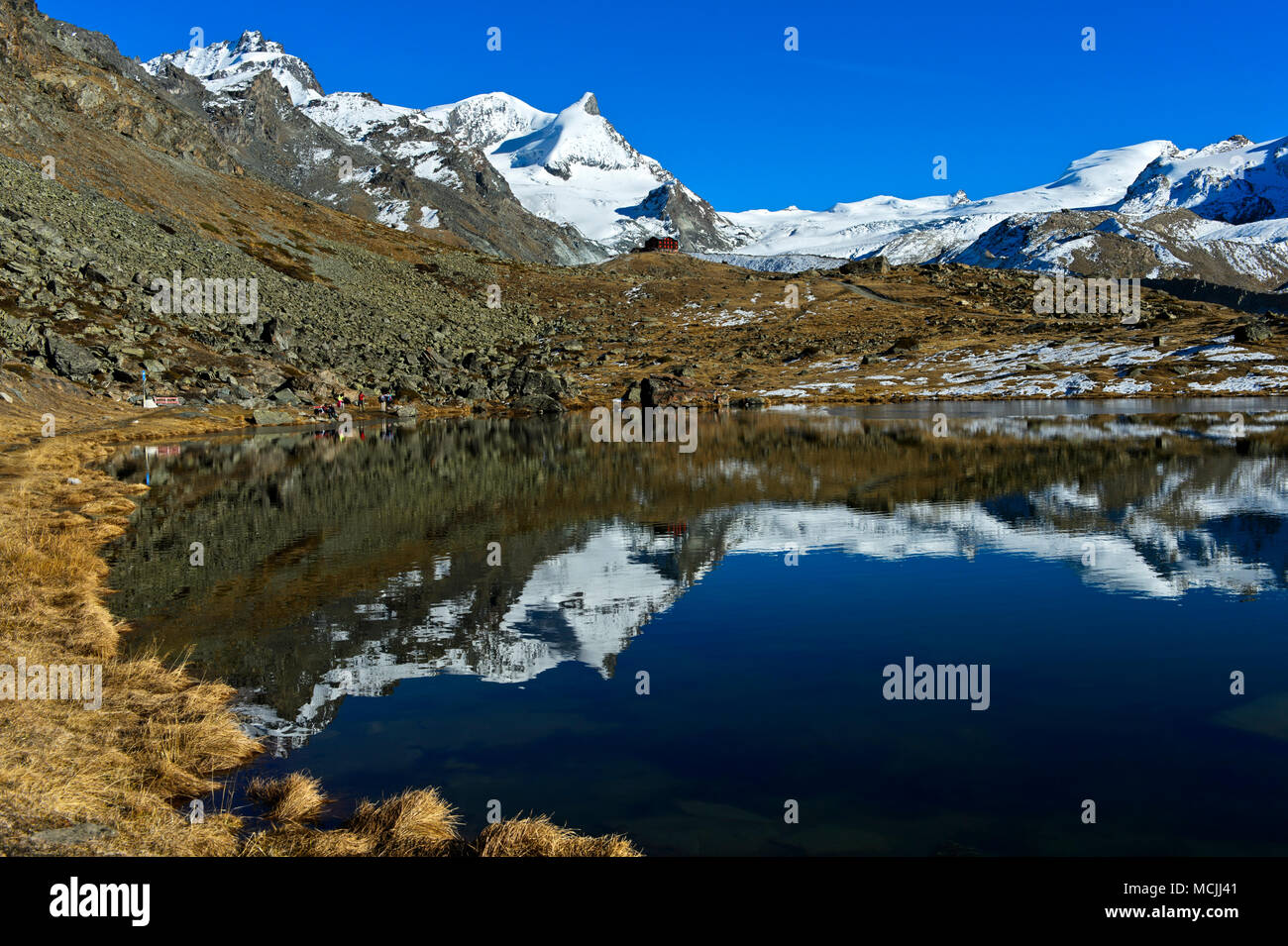 Lake Stellisee with view to the mountain restaurant Fluhalp and summits ...