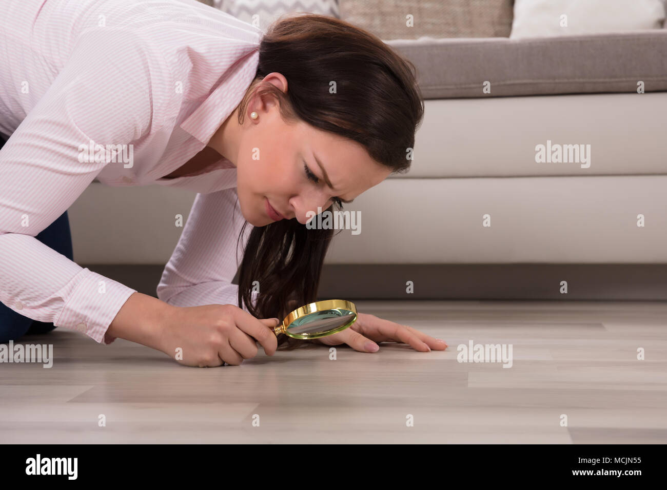 Side View Of A Young Woman Looking At Hardwood Floor Through Magnifying ...