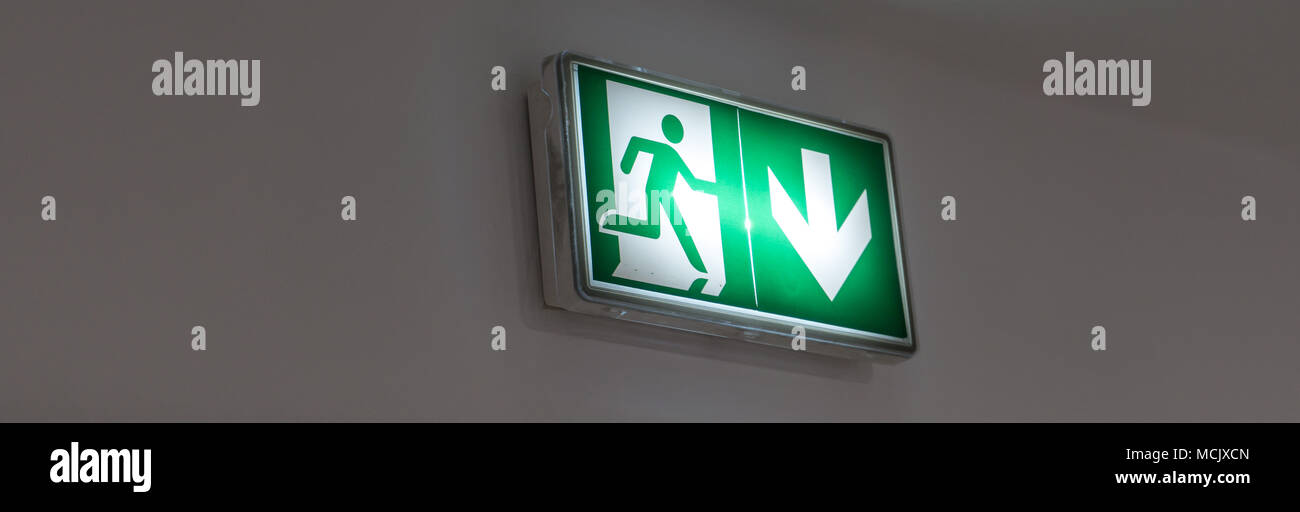 Emergency exit sign in a building glowing green Stock Photo - Alamy