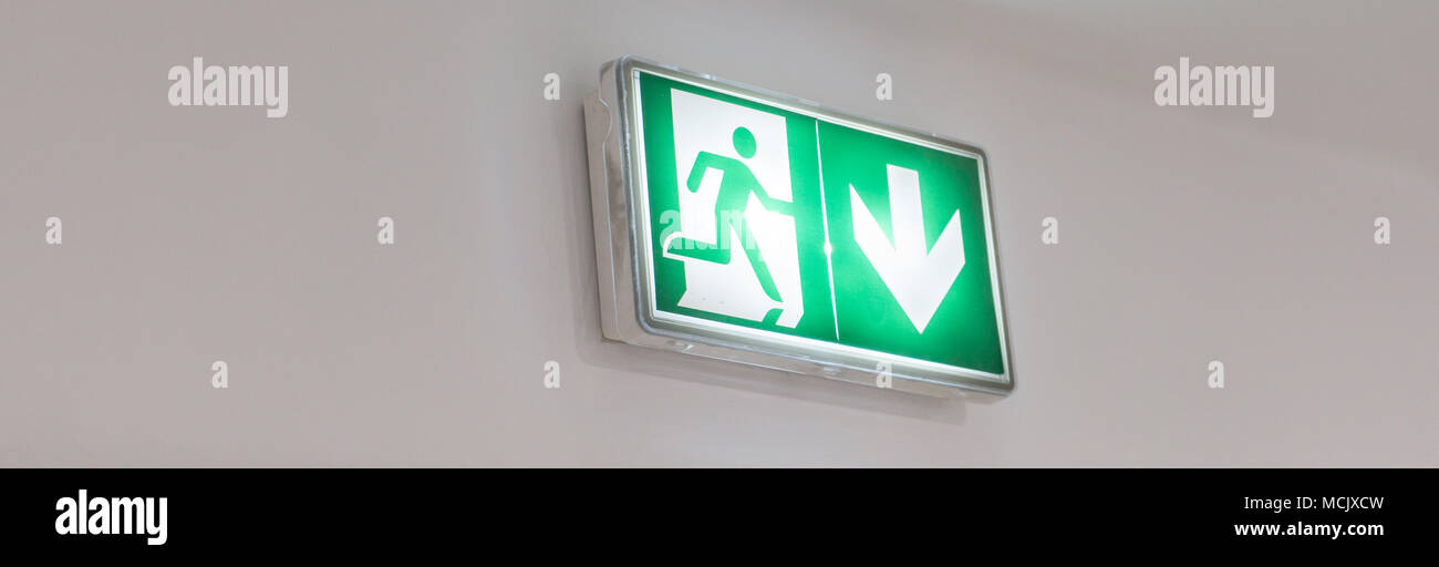 Emergency exit sign in a building glowing green Stock Photo - Alamy