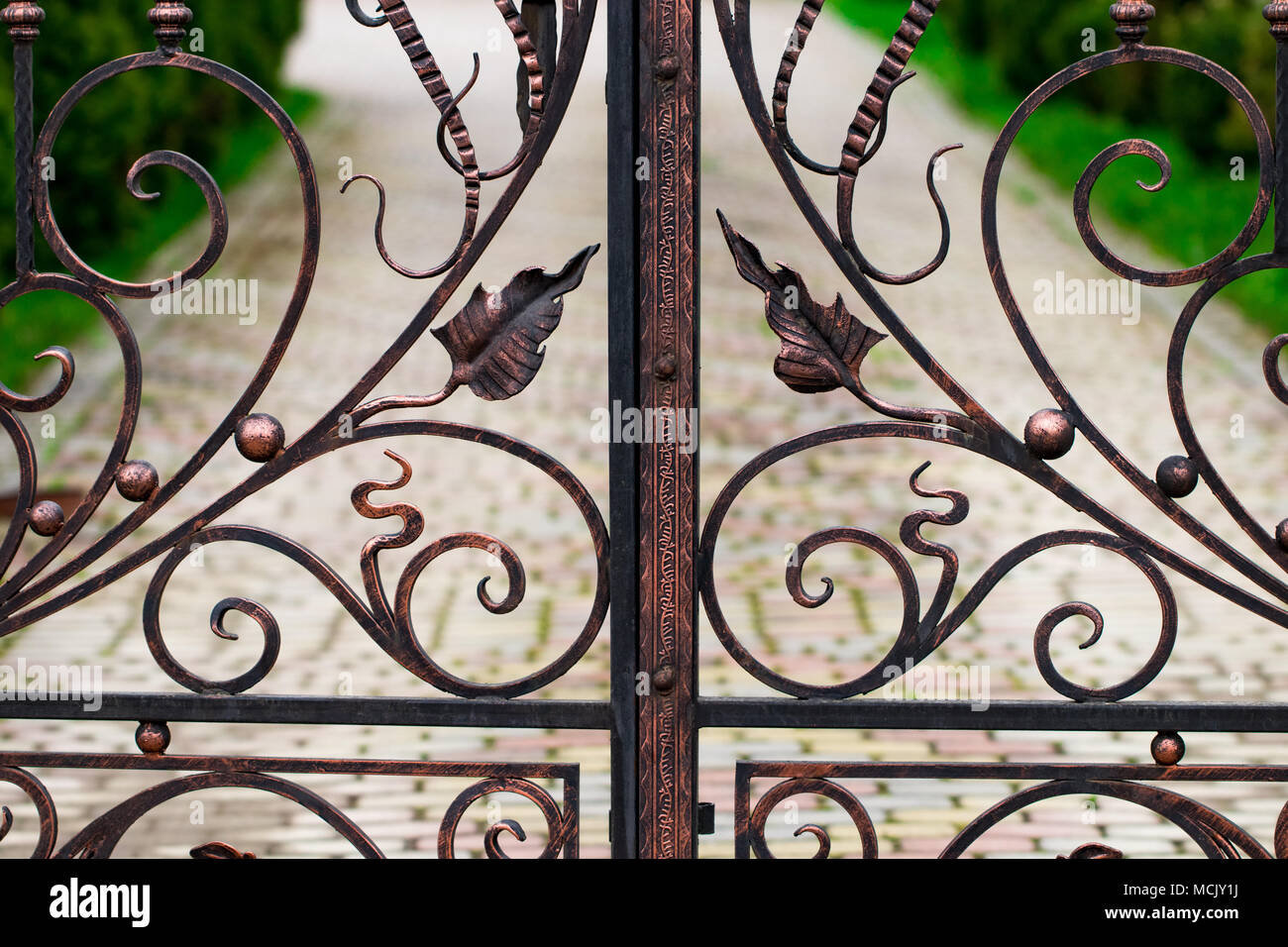 A closed forged metal gate looking onto a garden path Stock Photo - Alamy