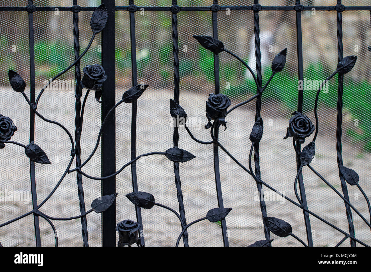 A closed forged metal gate looking onto a garden path Stock Photo - Alamy